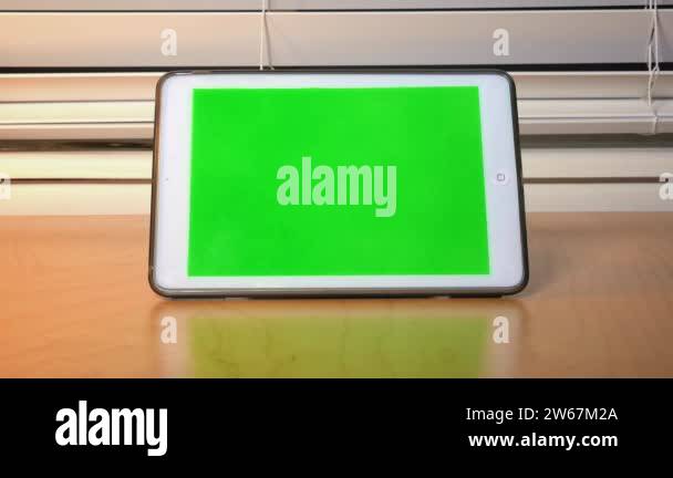 A person turns on then touches the screen of an iPad. Green screen with ... A person turns on then touches the screen of an iPad. Green screen with ...