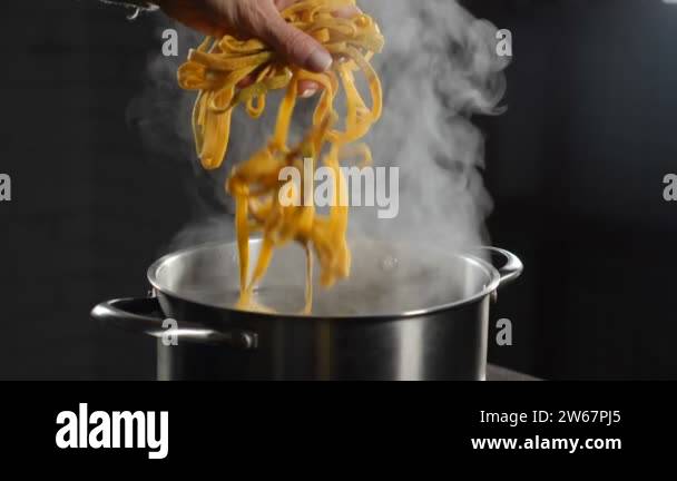 Putting raw pasta into boiling water. steam goes up in slow motion ...