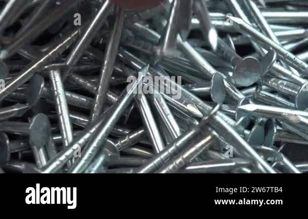 Metal steel nails for construction work falling on a rotating surface ...