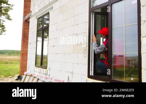 The window installer adjusts the hinges and checks new windows in the ...