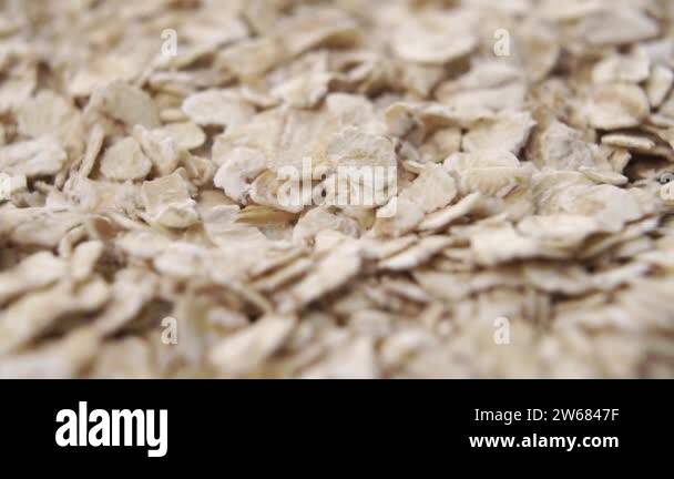 Oatmeal dry cereal flakes fall in a heap in slow motion close-up ...