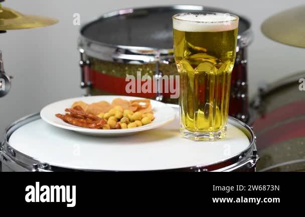 Glass of light beer on professional drum set closeup. Drumsticks, drums ...