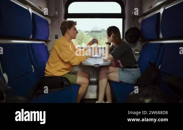 Beautiful young man and woman sit in a train compartment and travel ...