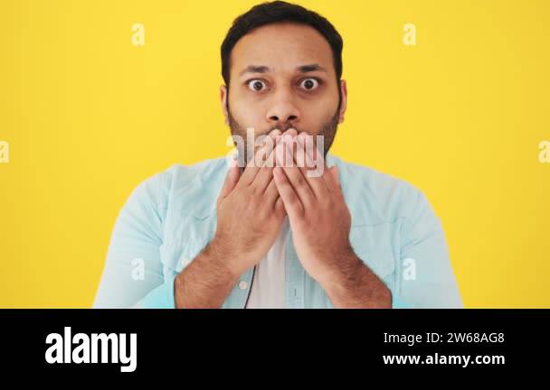 A close-up view of a shocked indian man is hiding his mouth with his ... A close-up view of a shocked indian man is hiding his mouth with his ...