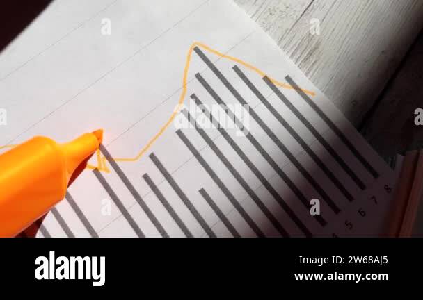 Close-up of a woman drawing a diagram with an orange marker. The female ...