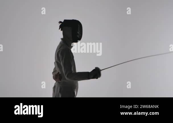 Side view portrait of young guy with rapier in his hands on gray studio ...