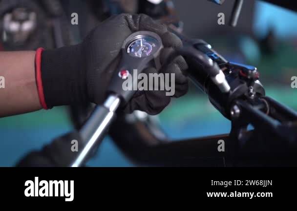 mechanics hand in gloves using a pressure gauge pump to adjust the ...
