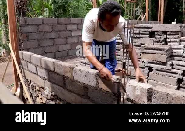 Bricklayer works at construction site, lays bricks in masonry, builds ...