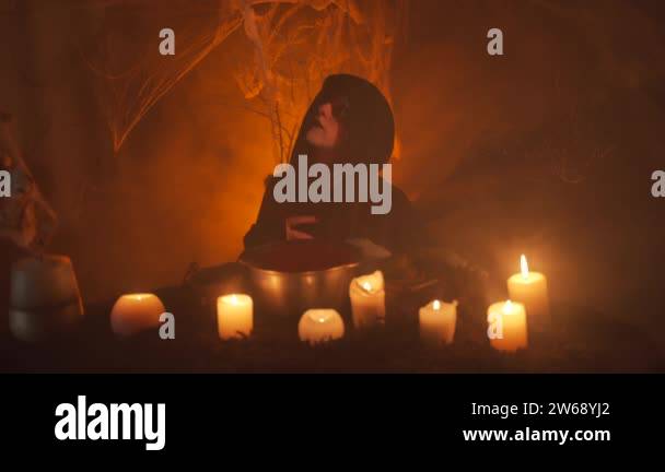 Witch's house. Scary witch in hood does voodoo black magic ritual on ...