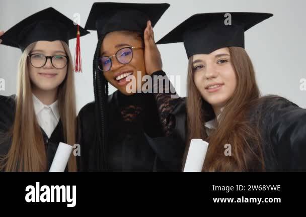 Three young happy graduate women of different nationalities stand ...
