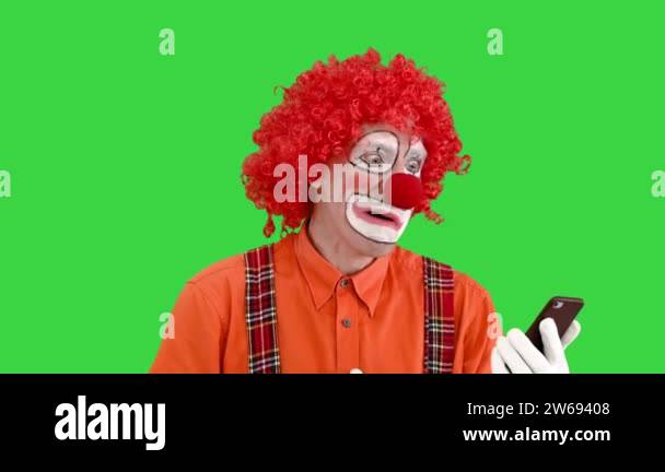 Funny clown looking at smartphone and reacting on what he sees on a ...