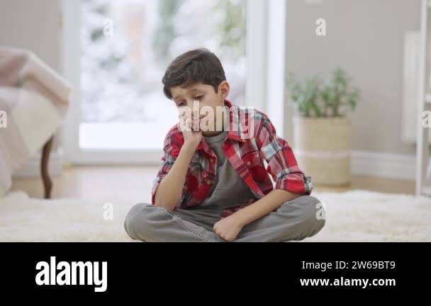 Sad frustrated Middle Eastern boy sitting on carpet at home thinking ...