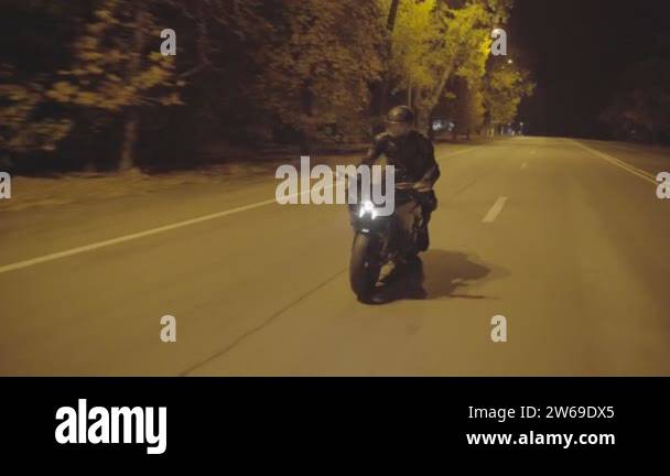 Male biker moving on his modern motorcycle at evening city street ...