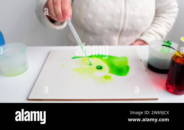 woman applies green paint with a pipette, inflates it, abstract spots ...