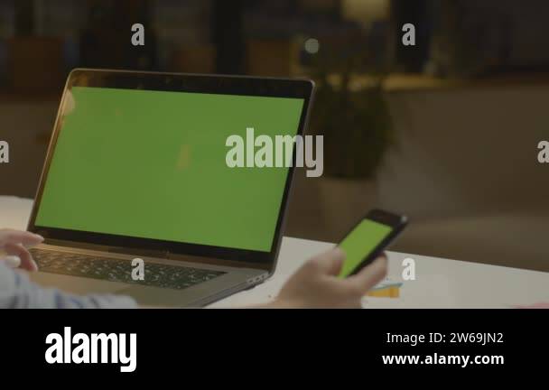 Female hand scrolling phone with green screen. Laptop and phone with chroma key Stock Video ...