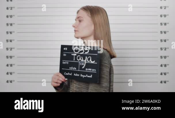 Mugshot of arrested female person holding sign while being photographed ...