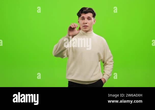 The man is standing and looking at the camera. He is raising his hand ...