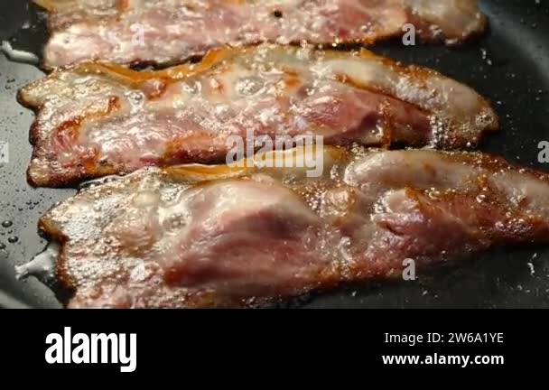 Fry the bacon in a pan. A slice of pork bacon is prepared in its own ...