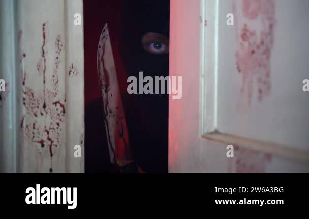 Serial maniac in balaclava holding bloody knife in hands and escaping ...