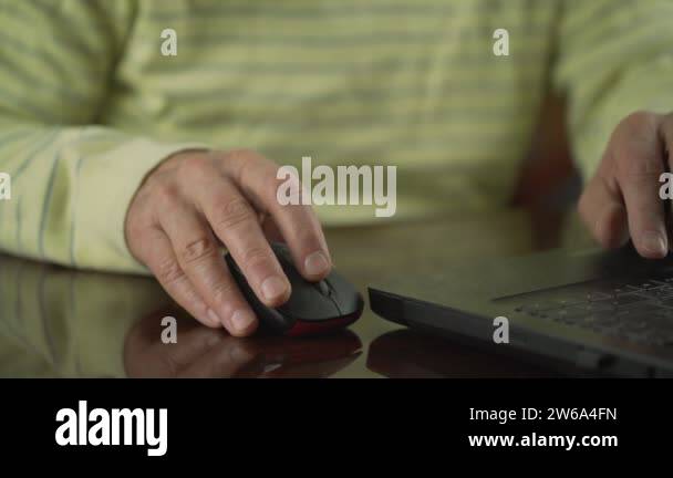 Hand of elderly man turns wheel of computer mouse and types text on ...