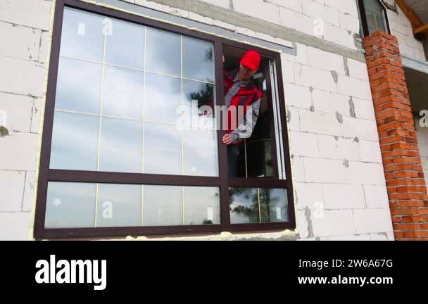 The window installer adjusts the hinges and checks new windows in the ...