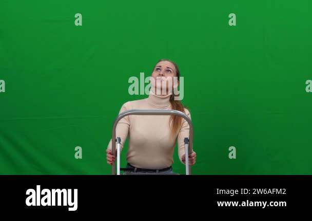 Caucasian woman walking up the ladder trying to reach something at top ...