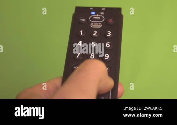 Male hand changing channels with remote control on a green screen ...