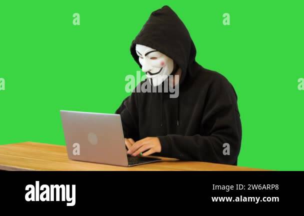Hacker with Vendetta mask on working on a laptop on a Green Screen ...