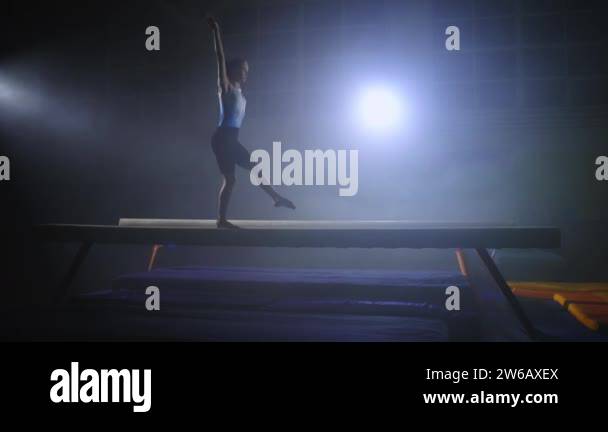 young sportswoman is rehearsing her sport performance on balance beam ...