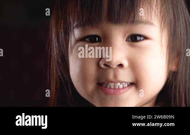 Close-up face portrait of cute little girl playfully looking at the ...