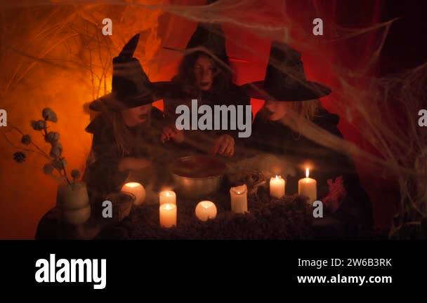 Three young girls dressed in witch's outfit are conjuring over the ...