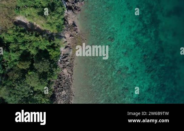 Top down aerial view of the tropical sea with wave crashing against an empty stone rocks cliff ...