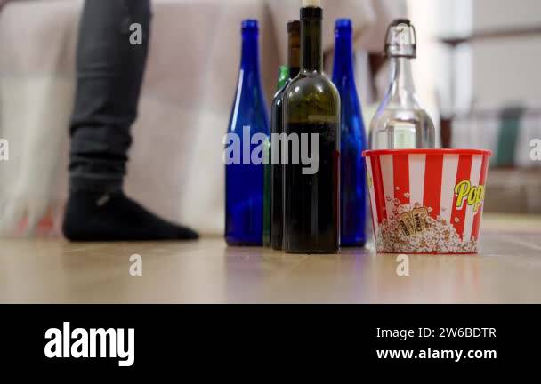 Alcohol bottles and popcorn on floor with legs of drunk man walking to ...