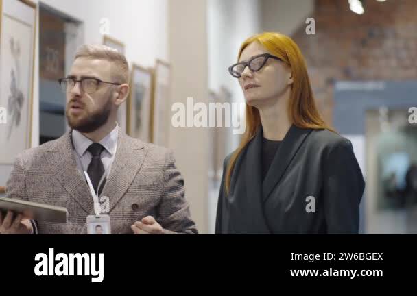 Professional male gallery docent holding clipboard and pointing at ...