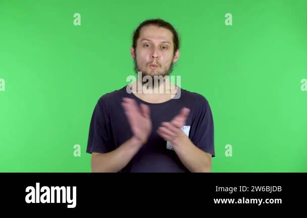 An impressed young bearded man applauds on a green screen. A young guy ...