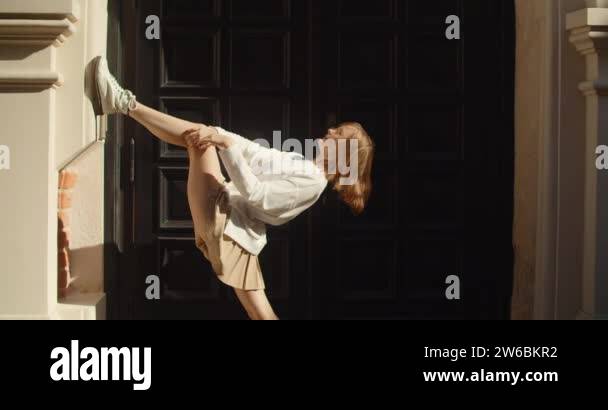 Flexible acrobatic woman does stretching exercise in old town ...