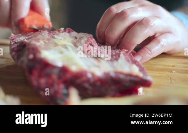 Man without gloves peeling dried meat on wooden board, professional ...
