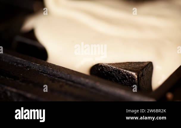 Raw pastry batter cooking in a waffle iron. The yeast dough bubbles and ...