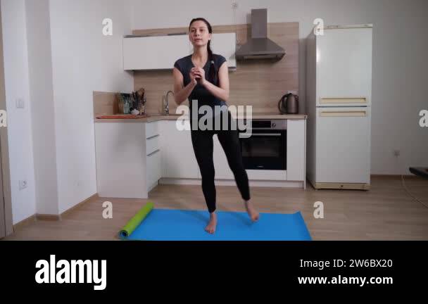 A brunette girl performs an exercise of waving her feet at home in the ...