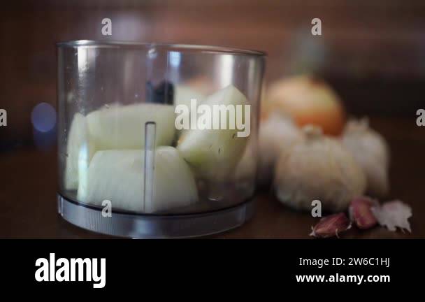 Crop anonymous female cook in apron adding garlic cloves in blender ...