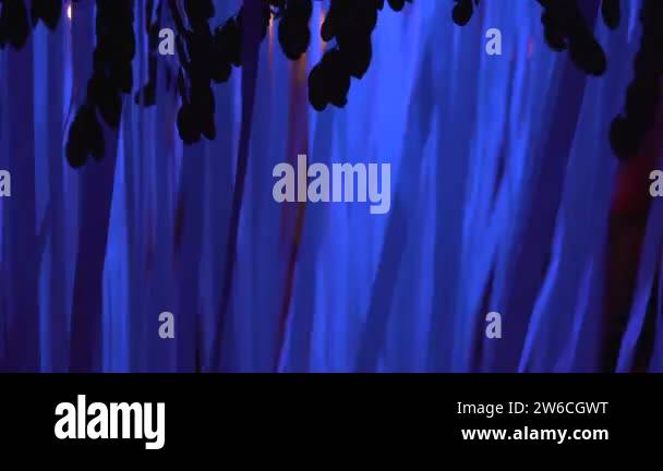 White ribbons sway in the wind in blue neon light on a dark night ...