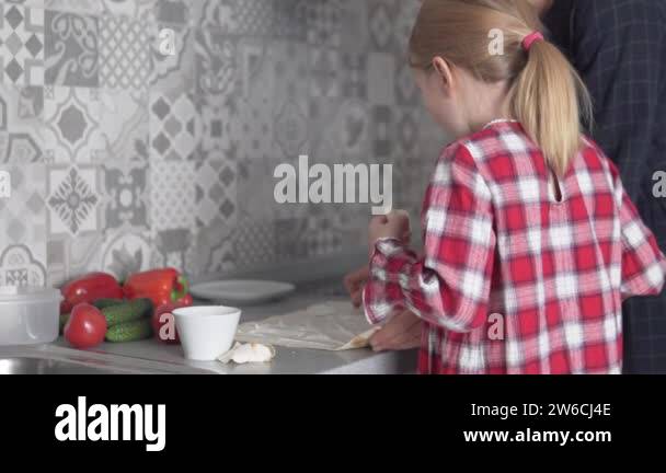 A little girl eats and cooks in the kitchen. The child spoons the curd ...