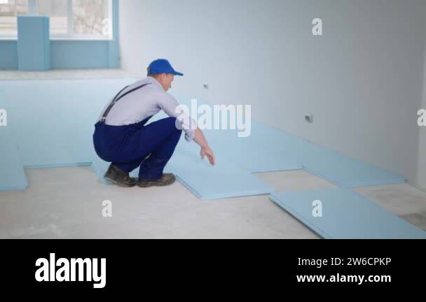 renovation of premises, young man in work clothes insulated floor with ...