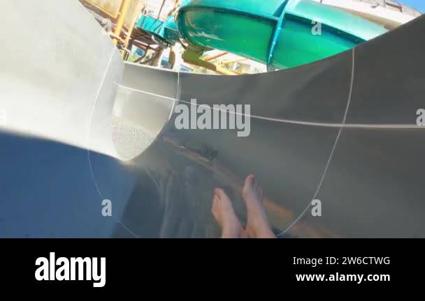 mens legs. a man in a camera in his hands rolls down a slide in a water ...