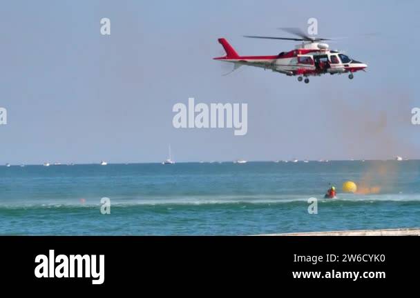 Team of firefighters performing sea rescue drill in helicopter lifting ...