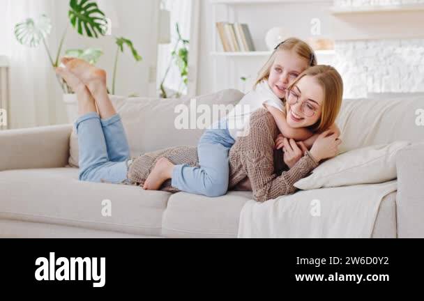 Baby with mom resting indoor on couch in cozy living room laughing ...