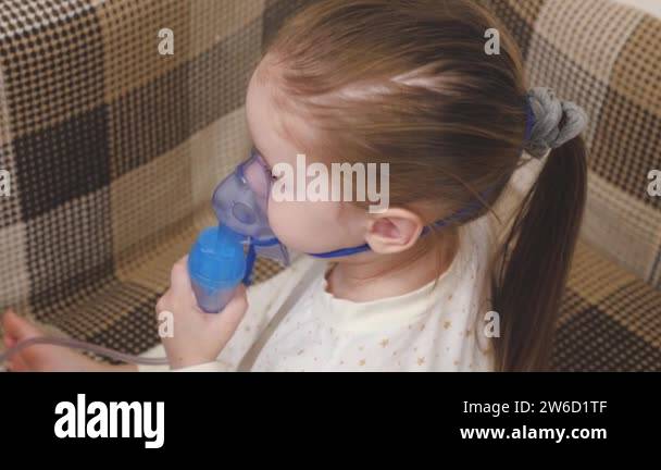 A cute baby in a mask is breathing through an inhaler. Home inhalation ...