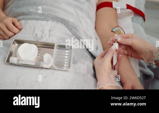 Nurse taking a blood sample from a patient lying in a hospital ward ...