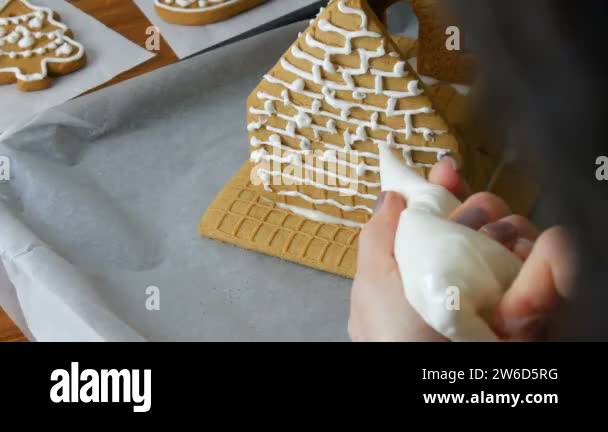 Woman decorates gingerbread house with pastry bag white sugar sweet ...