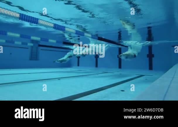 Moment of athletes jump into a pool captured underwater. Professional ...